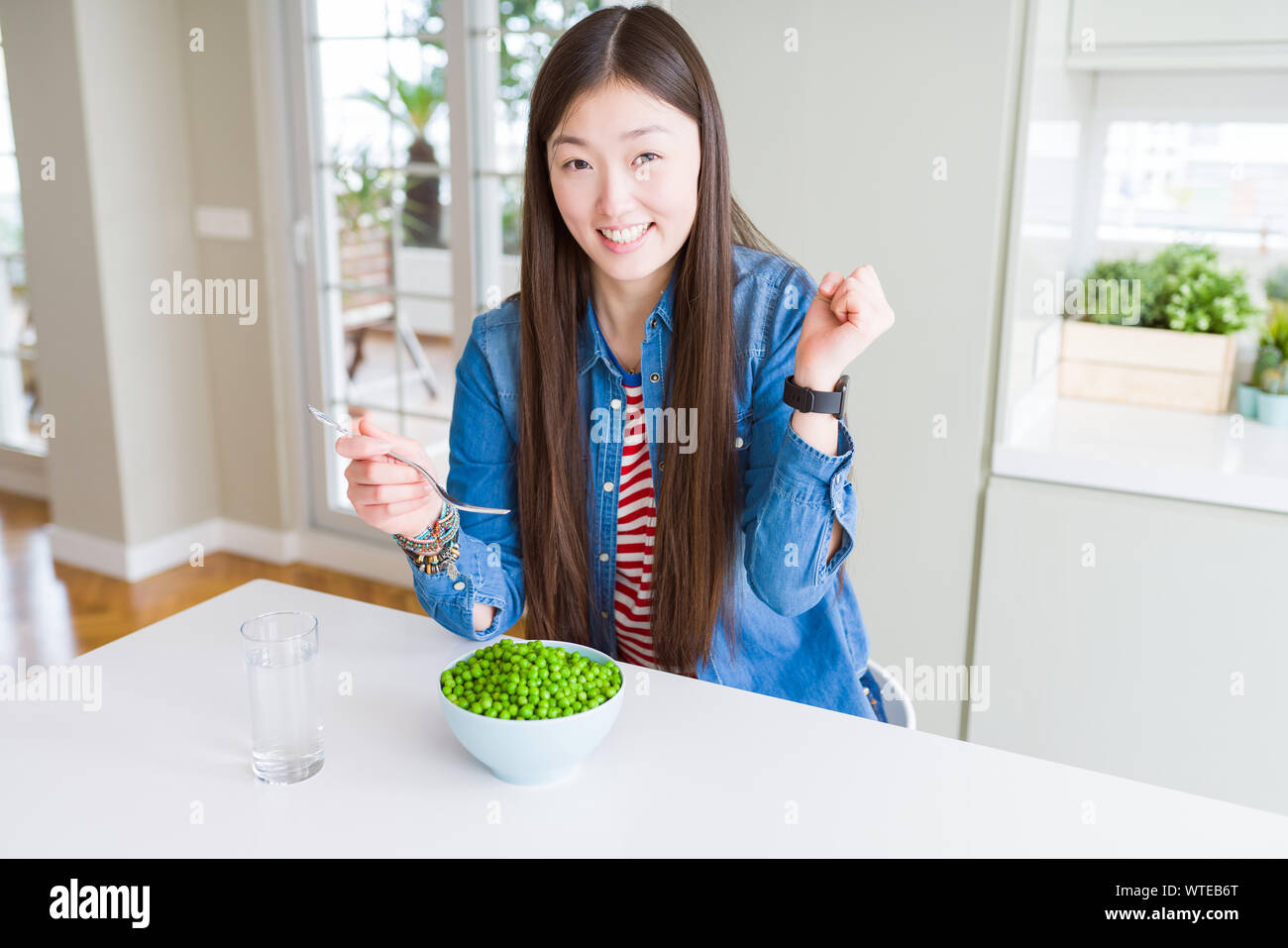 Beautiful Asian woman eating fresh green peas screaming proud and ...