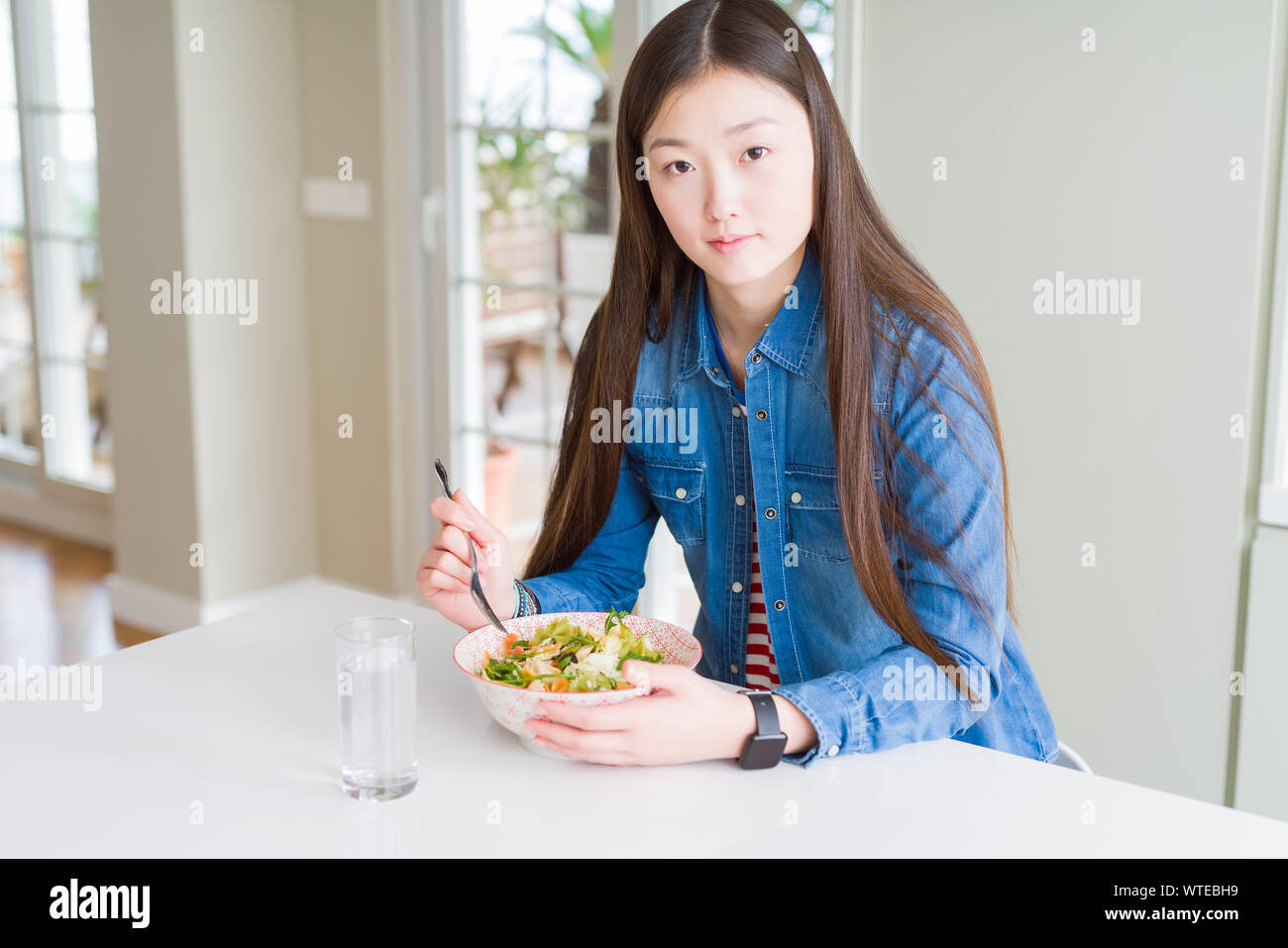 Beautiful Asian woman eating healthy pasta salad with a confident ...