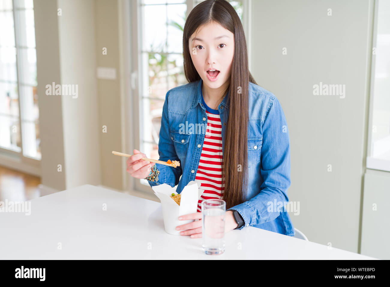Beautiful Asian woman eating asian rice in delivery box scared in shock ...