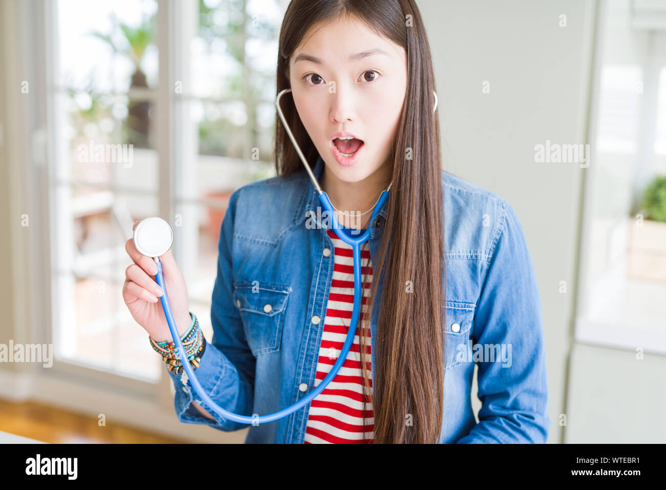 Beautiful Asian woman checking health care using stethoscope scared in ...