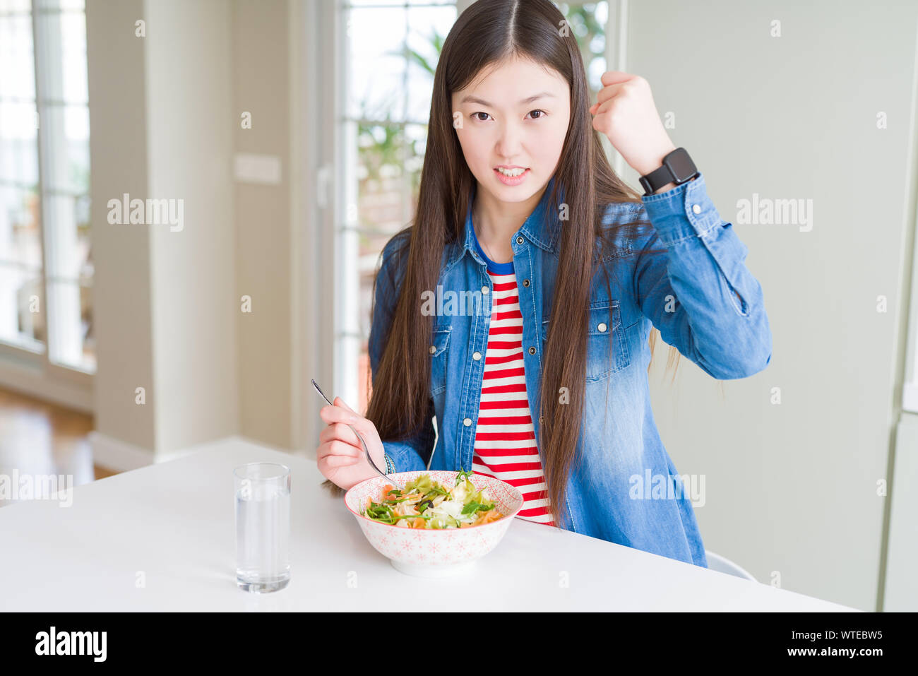 Beautiful Asian woman eating healthy pasta salad annoyed and frustrated ...