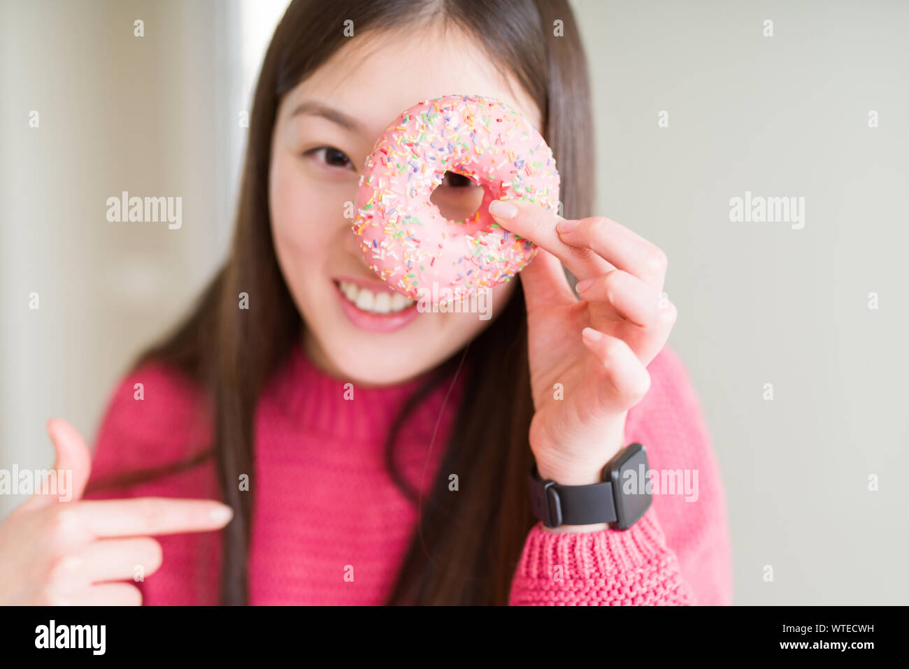 Beautiful Asian woman eating pink sugar donut with surprise face ...