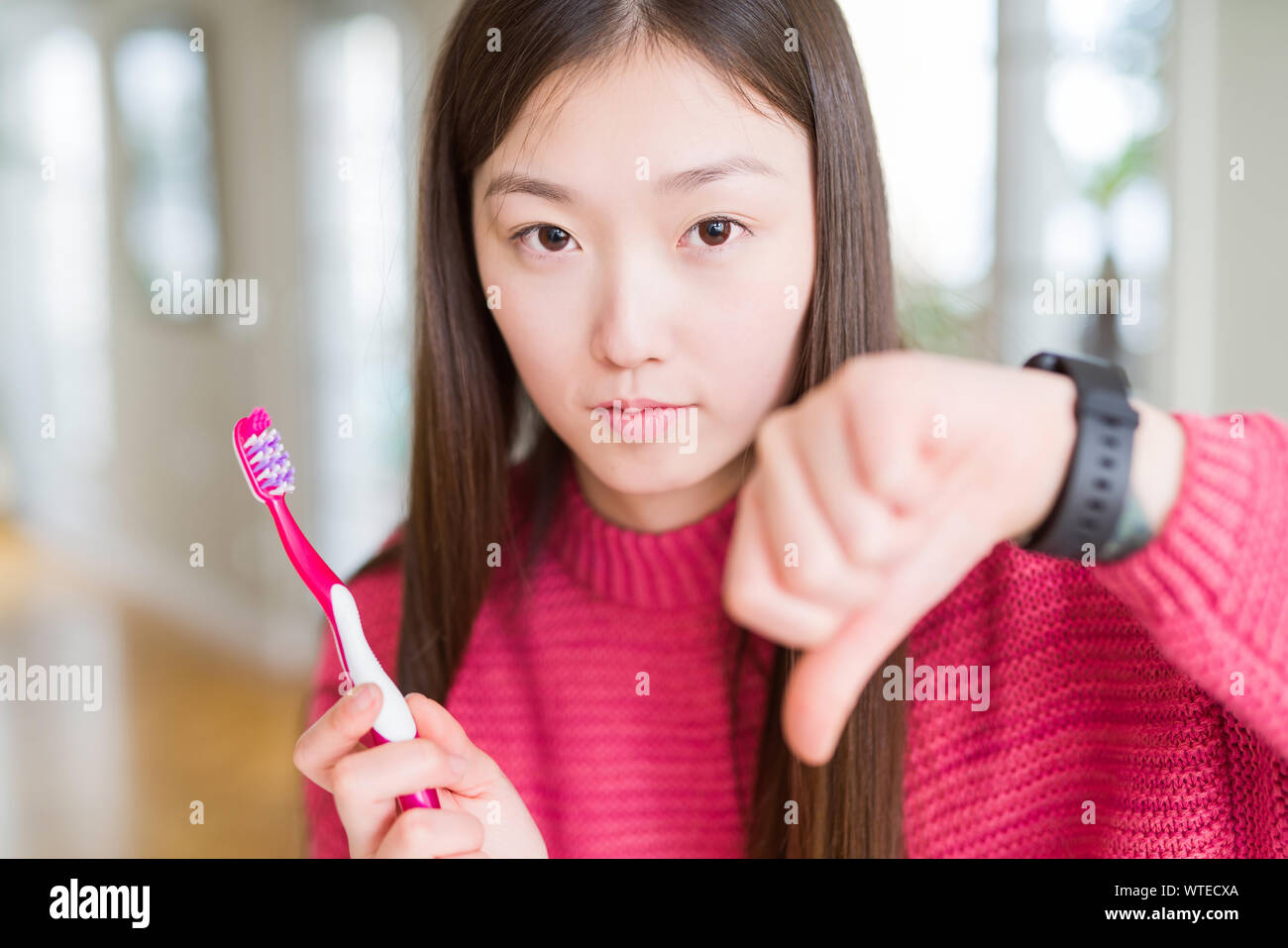 Beautiful Asian woman holding toothbrush with angry face, negative sign ...
