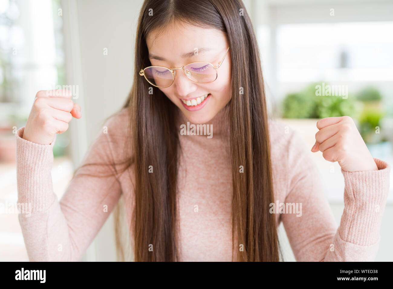 Beautiful Asian woman wearing glasses excited for success with arms ...