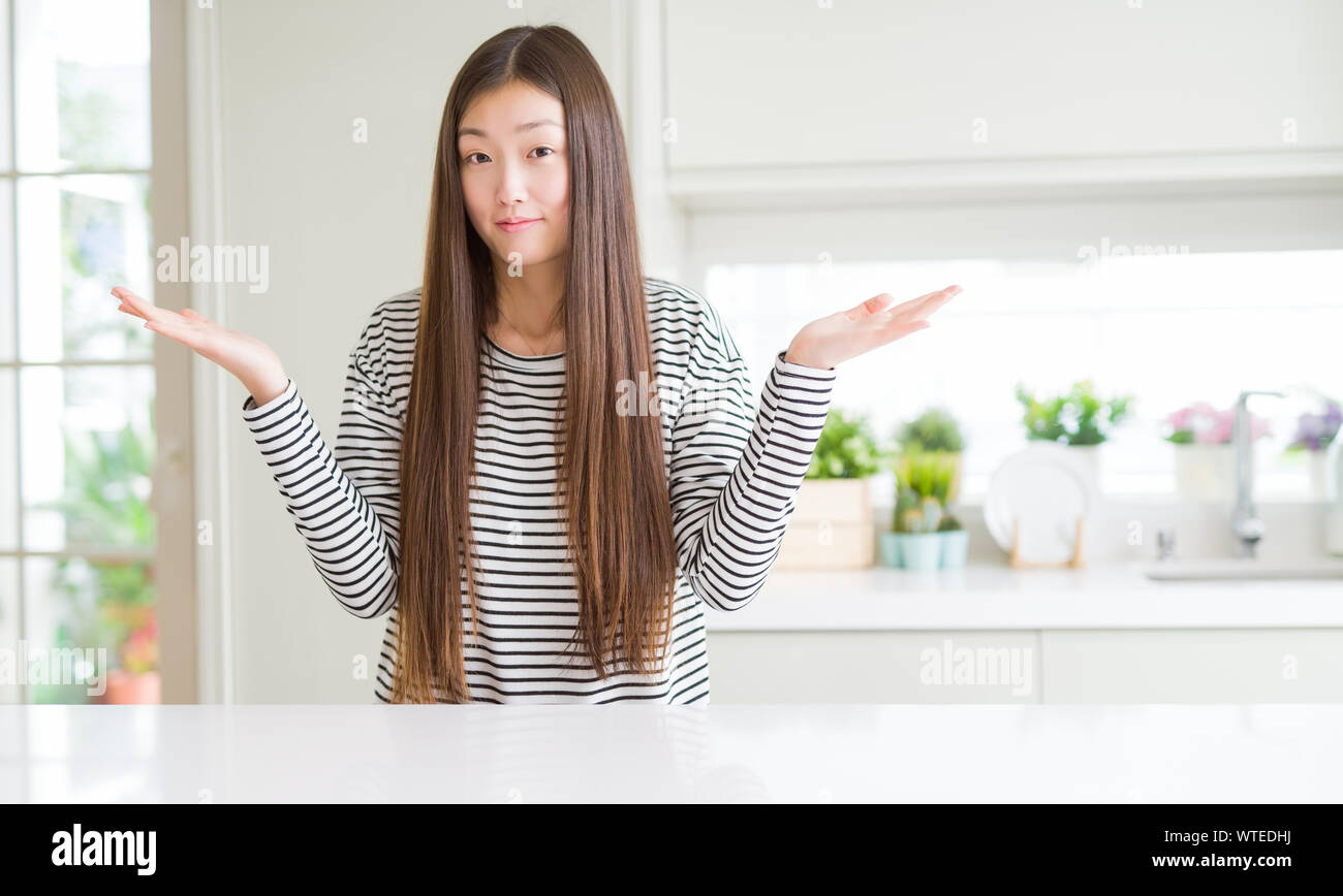 Beautiful Asian woman wearing stripes sweater clueless and confused ...