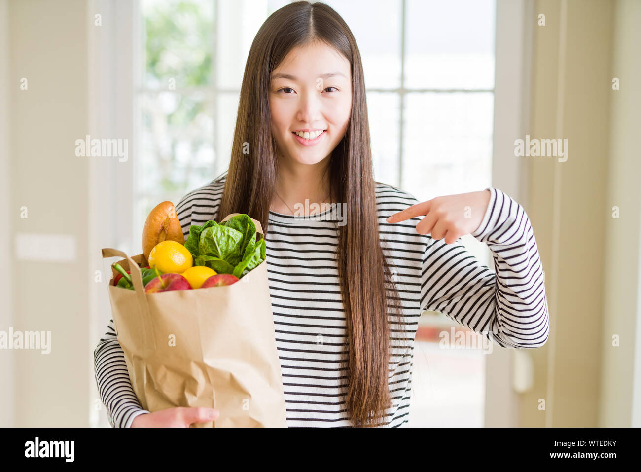 Beautiful Asian Woman Holding Paper Bag Of Fresh Groceries With