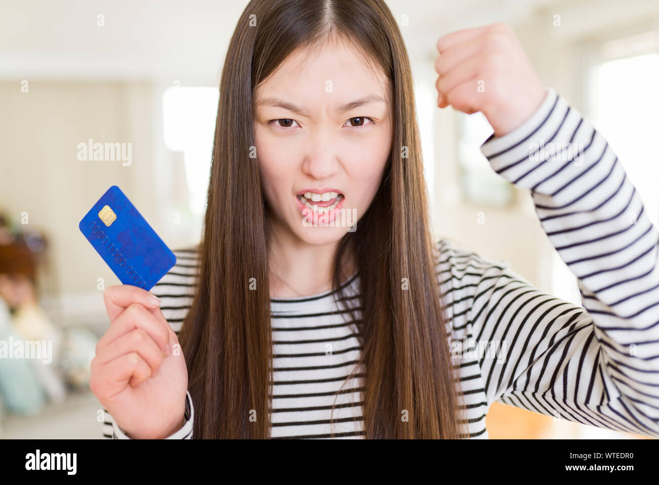 Beautiful Asian woman holding credit card annoyed and frustrated ...