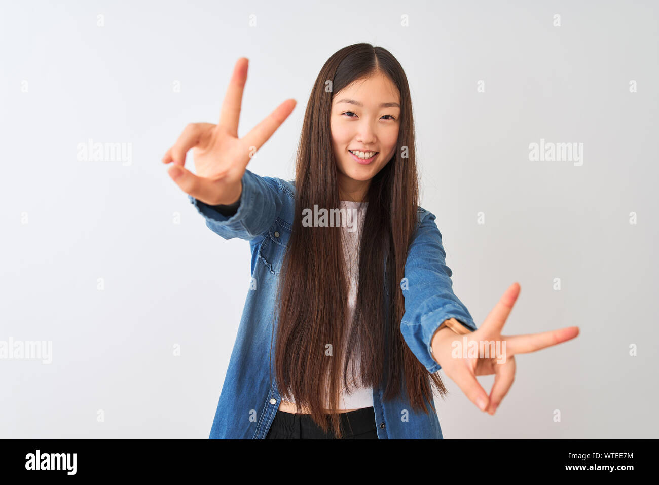 Young chinese woman wearing denim shirt standing over isolated white ...