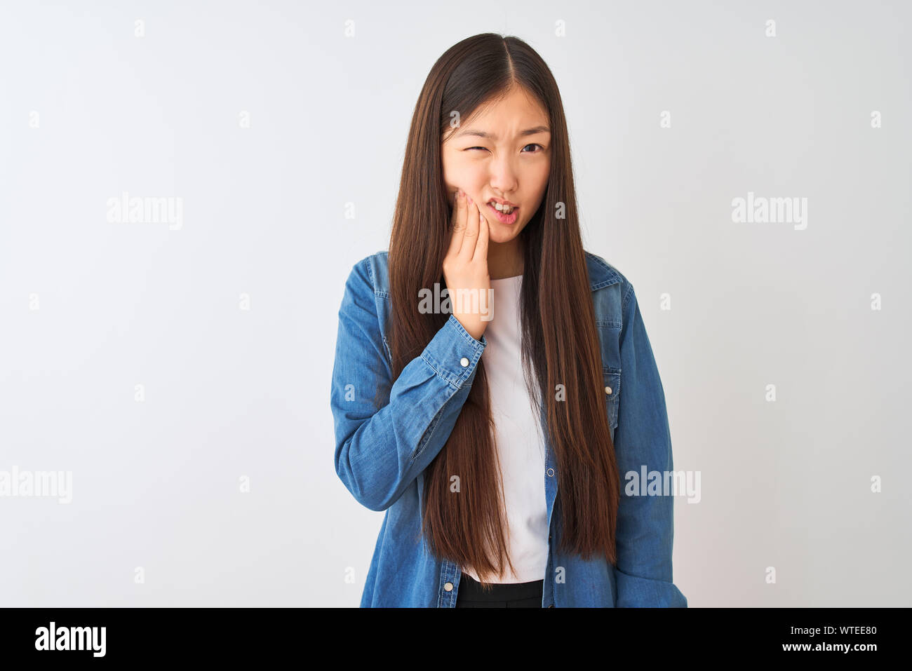 Young chinese woman wearing denim shirt standing over isolated white ...