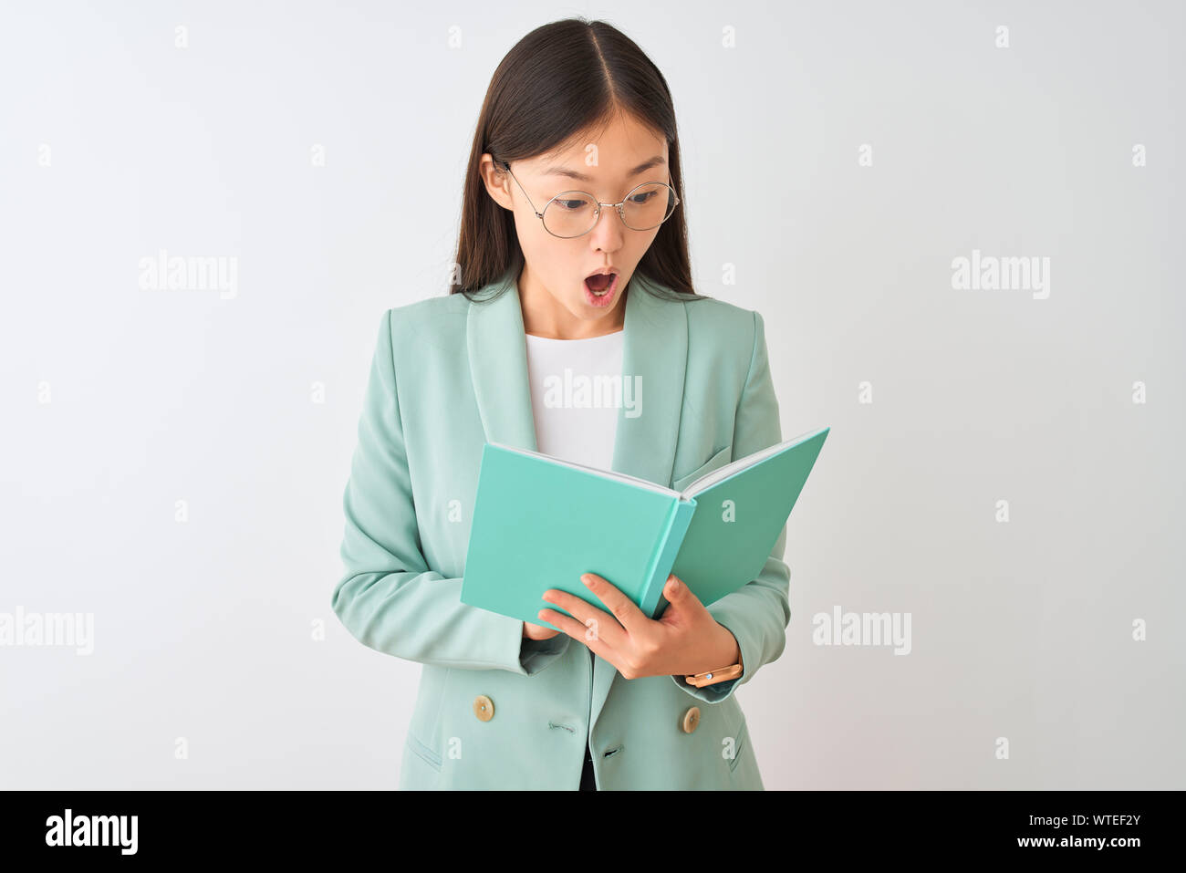 Young chinese student woman wearing glasses reading book over isolated ...