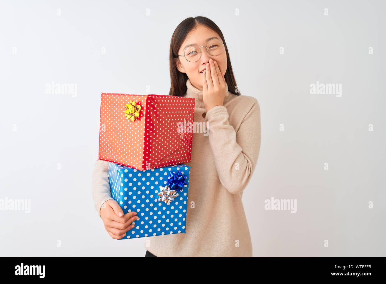 Young chinese woman holding birthday gifts over isolated white ...