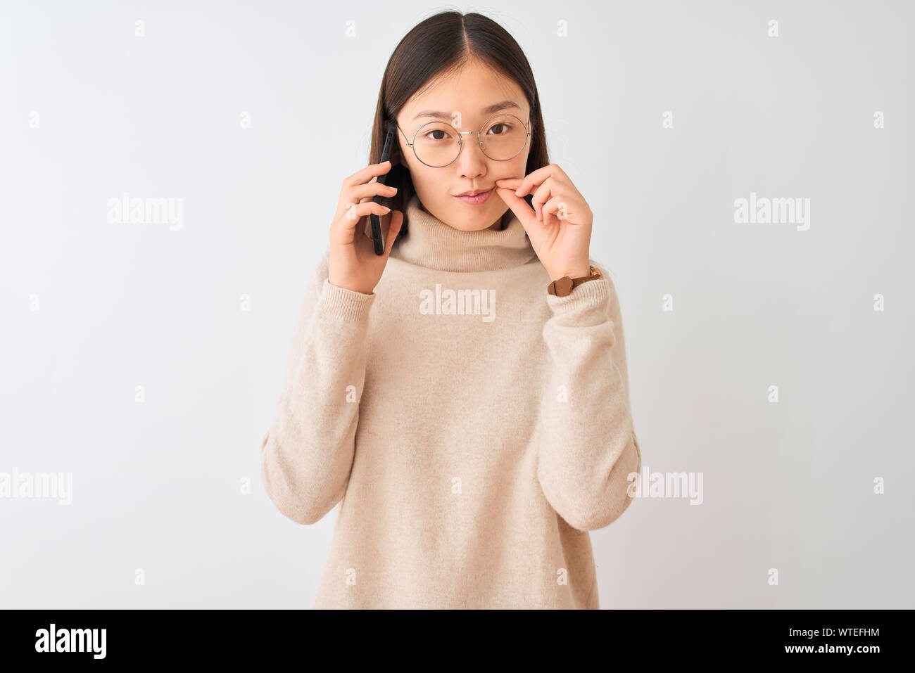 Young chinese woman talking on the smartphone over isolated white ...