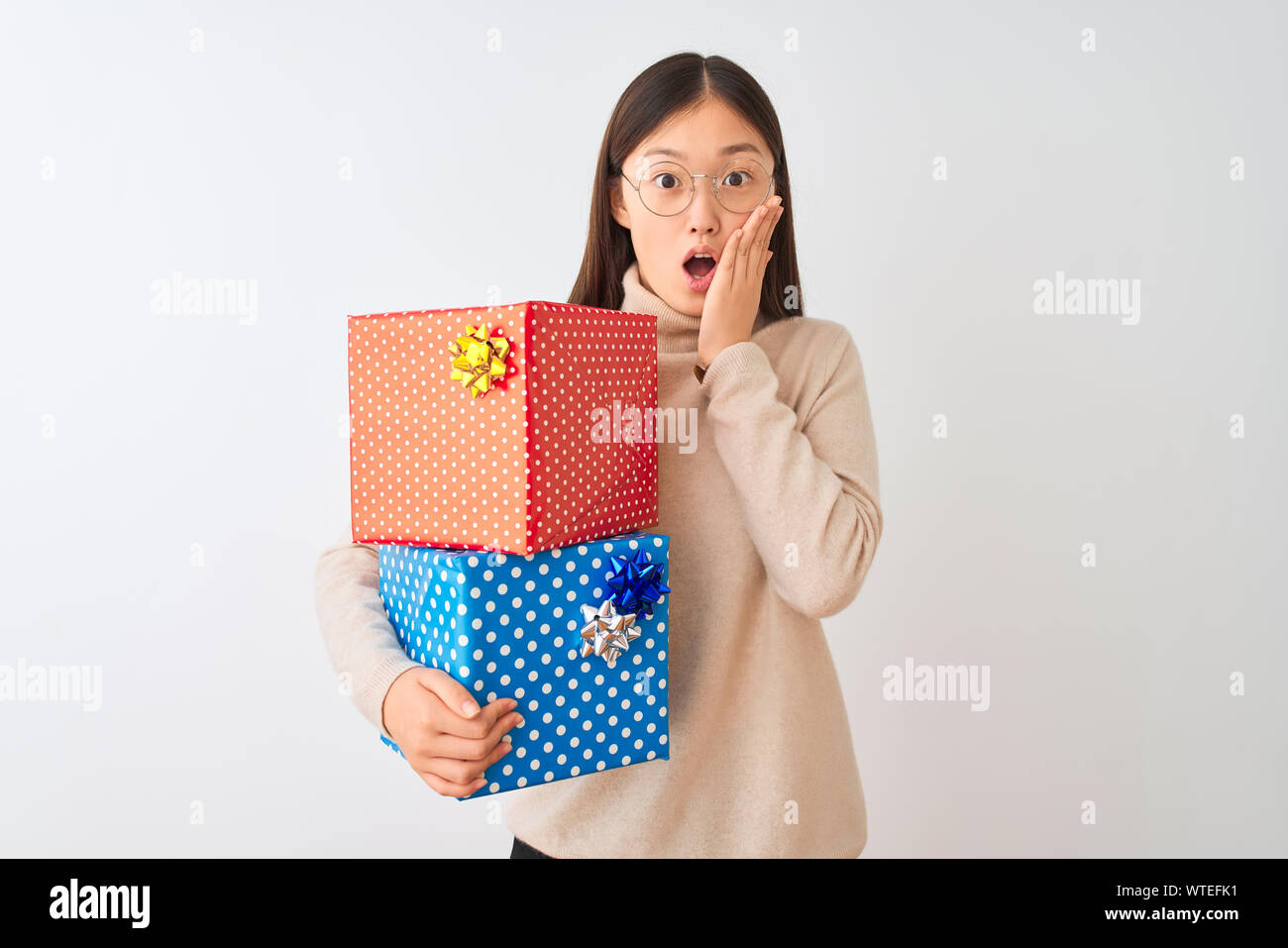 Young chinese woman holding birthday gifts over isolated white ...