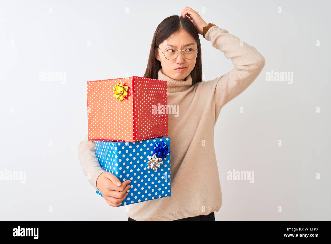 Young chinese woman holding birthday gifts over isolated white ...