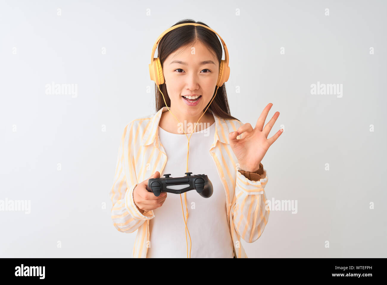 Chinese gamer woman playing video game using headphones over isolated ...