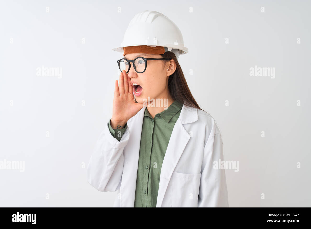 Young chinese engineer woman wearing coat helmet glasses over isolated ...