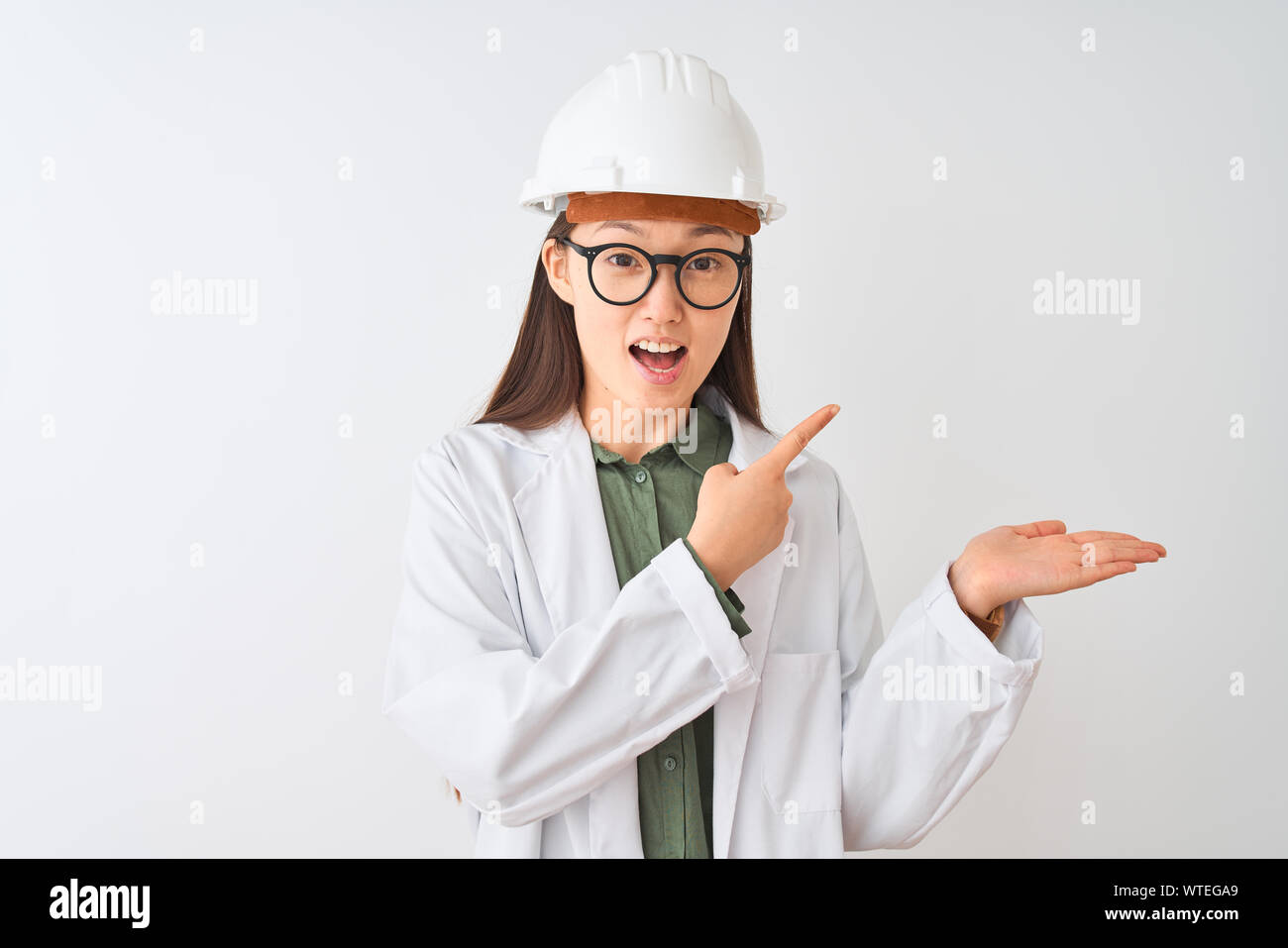 Young chinese engineer woman wearing coat helmet glasses over isolated ...