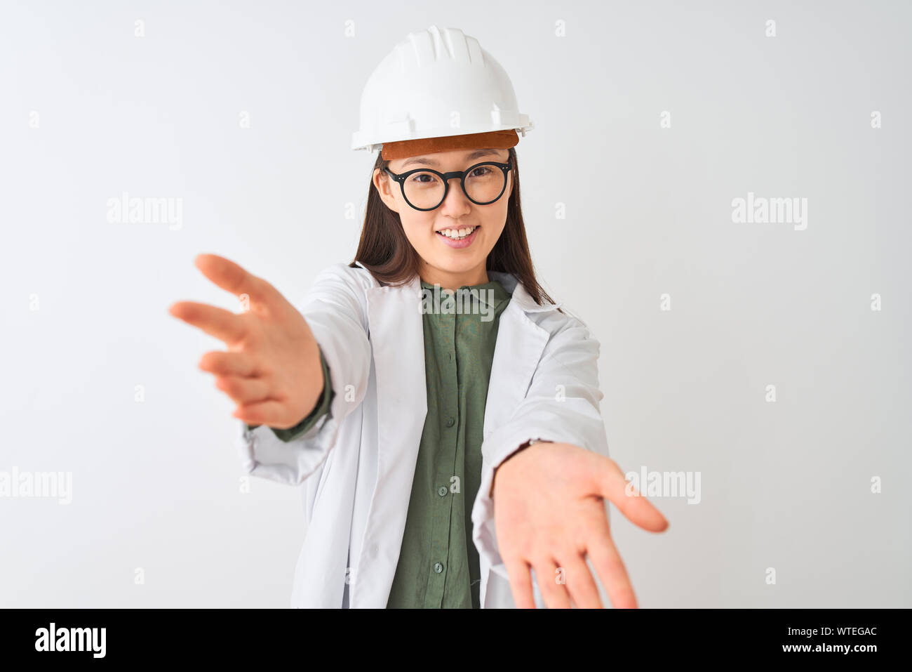 Young chinese engineer woman wearing coat helmet glasses over isolated ...