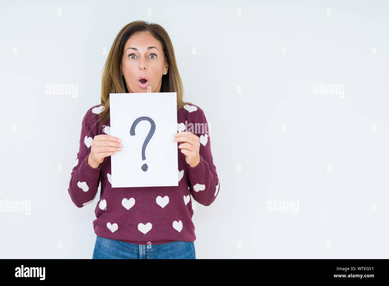 Middle age woman thinking and holding paper with question mark symbol ...