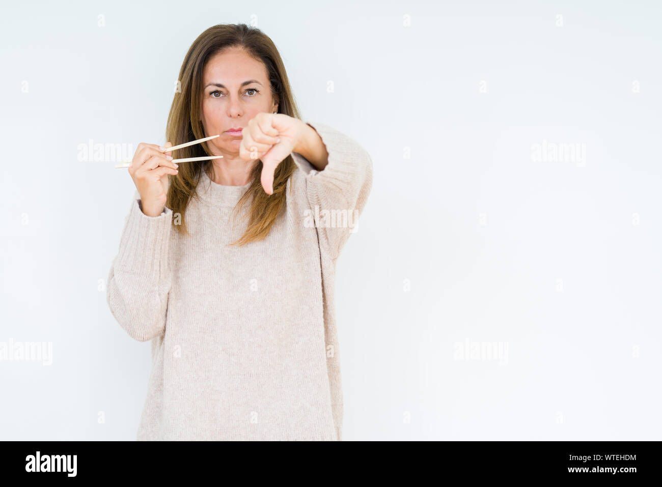 Middle age woman holding asian chopsticks over isolated background with ...