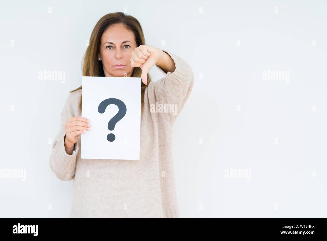 Middle age woman thinking and holding paper with question mark symbol ...