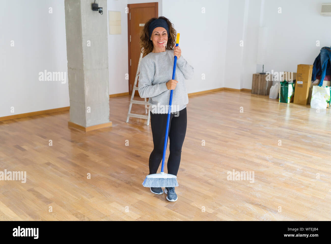 Middle age woman with curly hair working cleaning the house using a ...