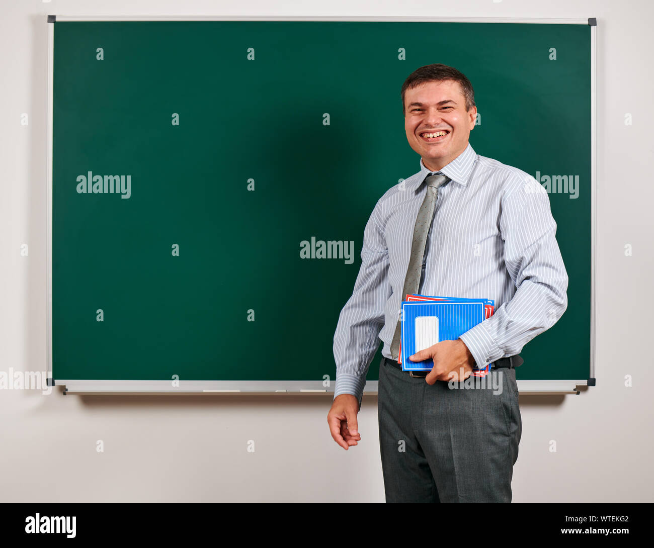 Portrait of a man as a teacher, posing at school board background ...