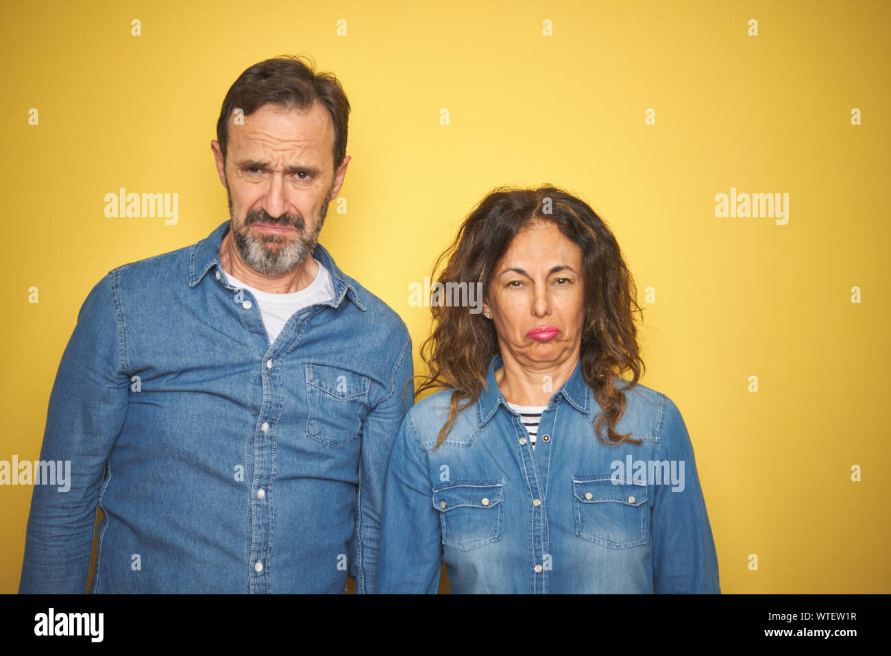 Beautiful middle age couple together standing over isolated yellow ...