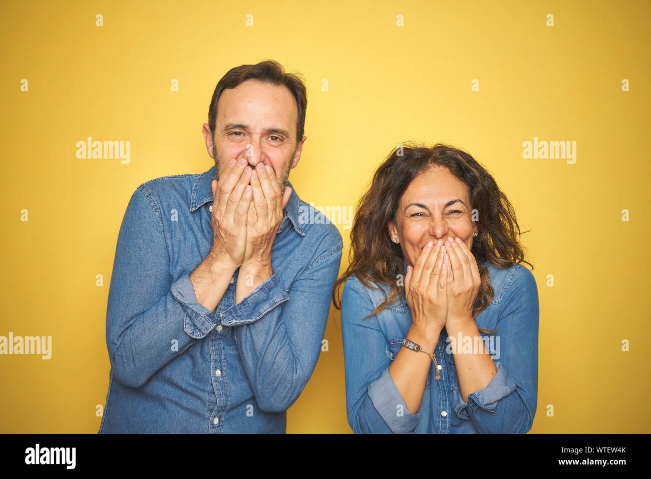 Beautiful middle age couple together standing over isolated yellow ...