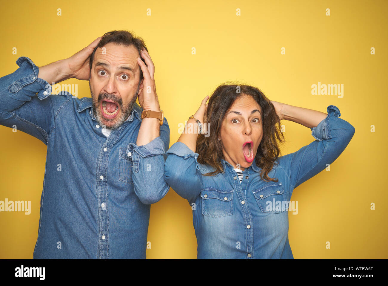 Beautiful middle age couple together standing over isolated yellow ...