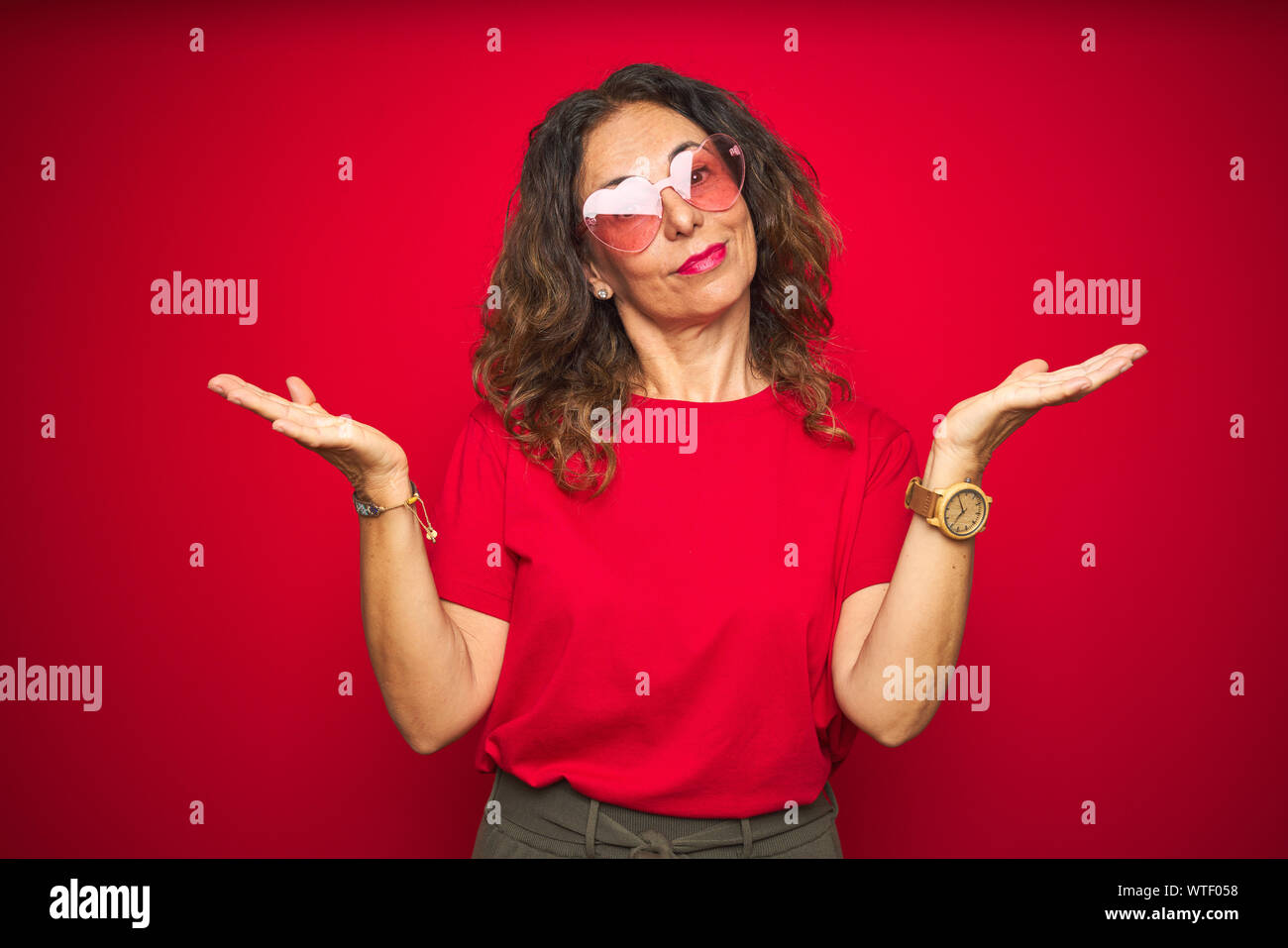 Middle age senior woman wearing cute heart shaped glasses over red ...