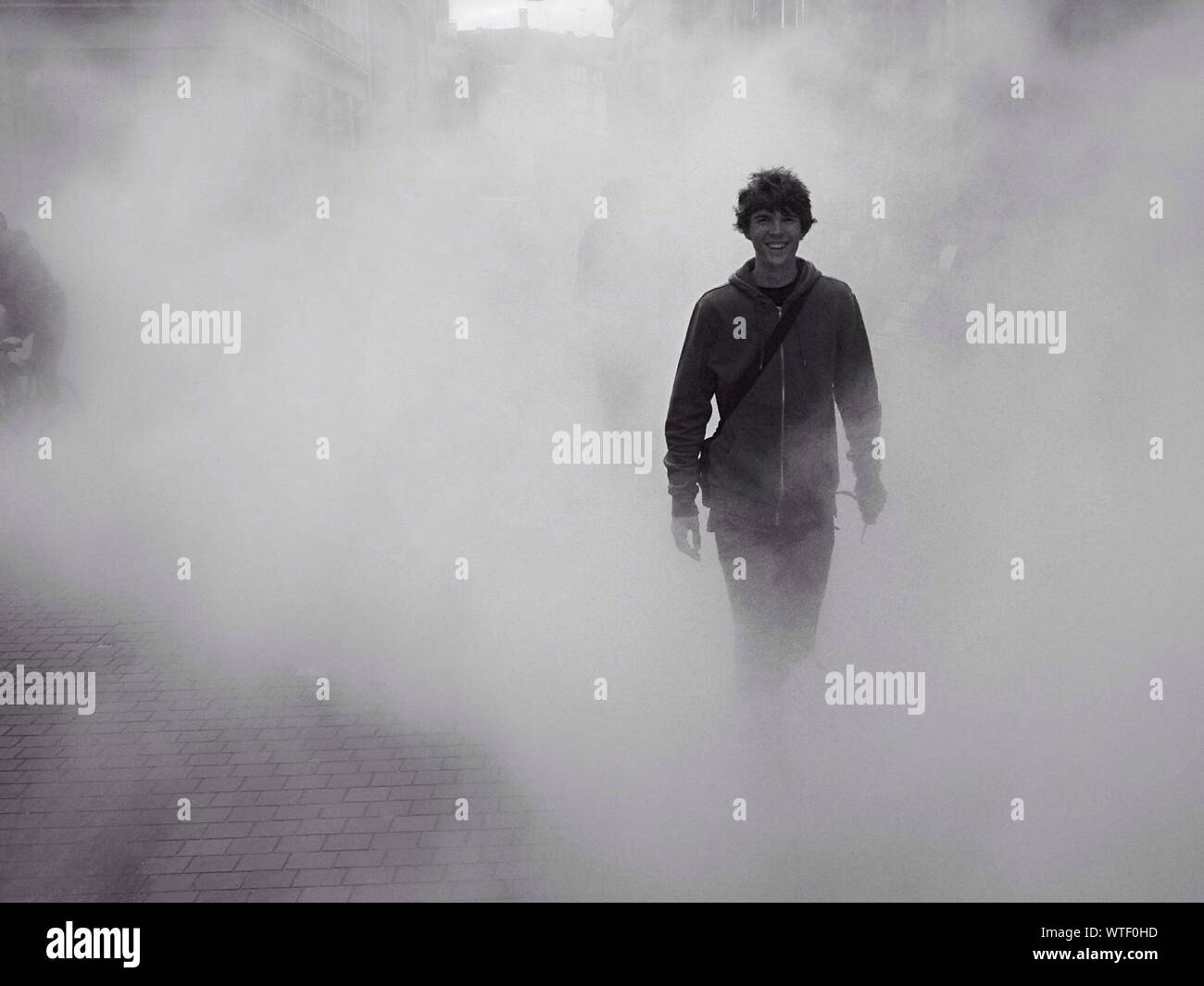 Happy Man Walking Amidst Smoke On Footpath Stock Photo - Alamy