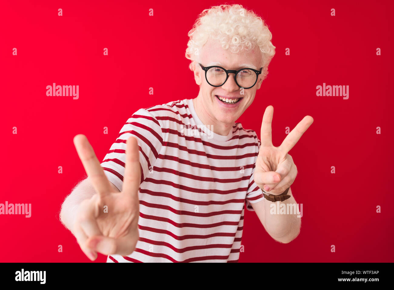 Young albino blond man wearing striped t-shirt and glasses over ...