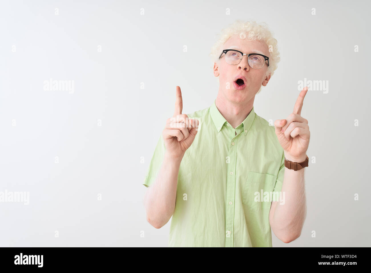 Young albino blond man wearing green shirt and glasses over isolated ...