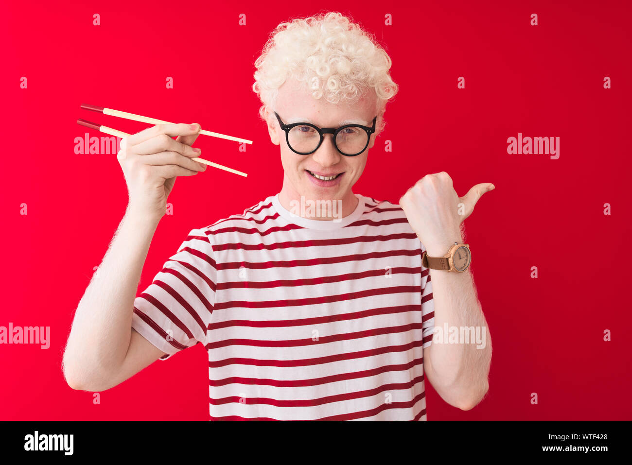 Young albino blond man holding chopsticks standing over isolated white ...