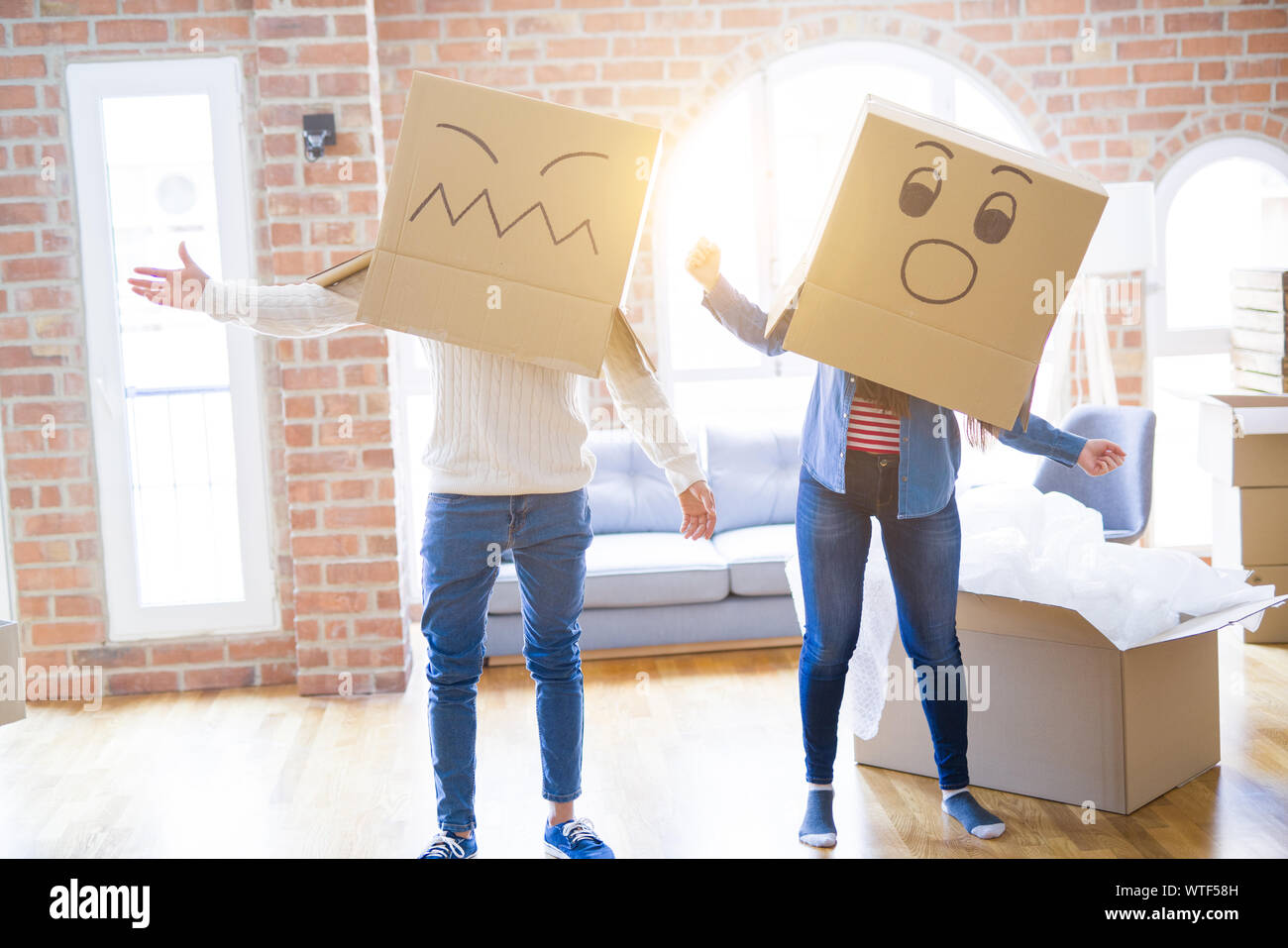 Crazy couple wearing boxes with funny faces over head, having fun happy ...