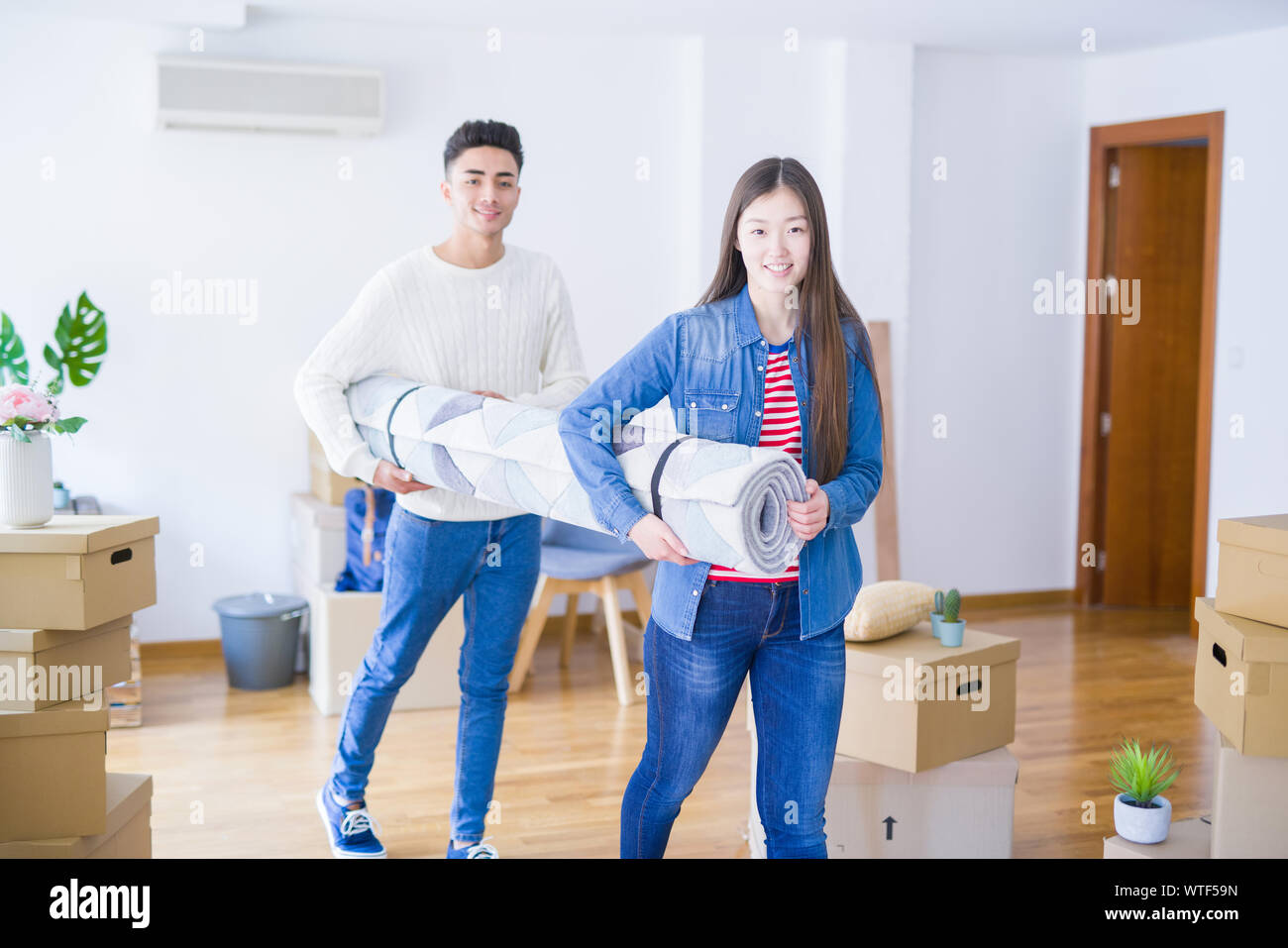 Beautiful young asian couple looking happy, holding rug smiling excited ...