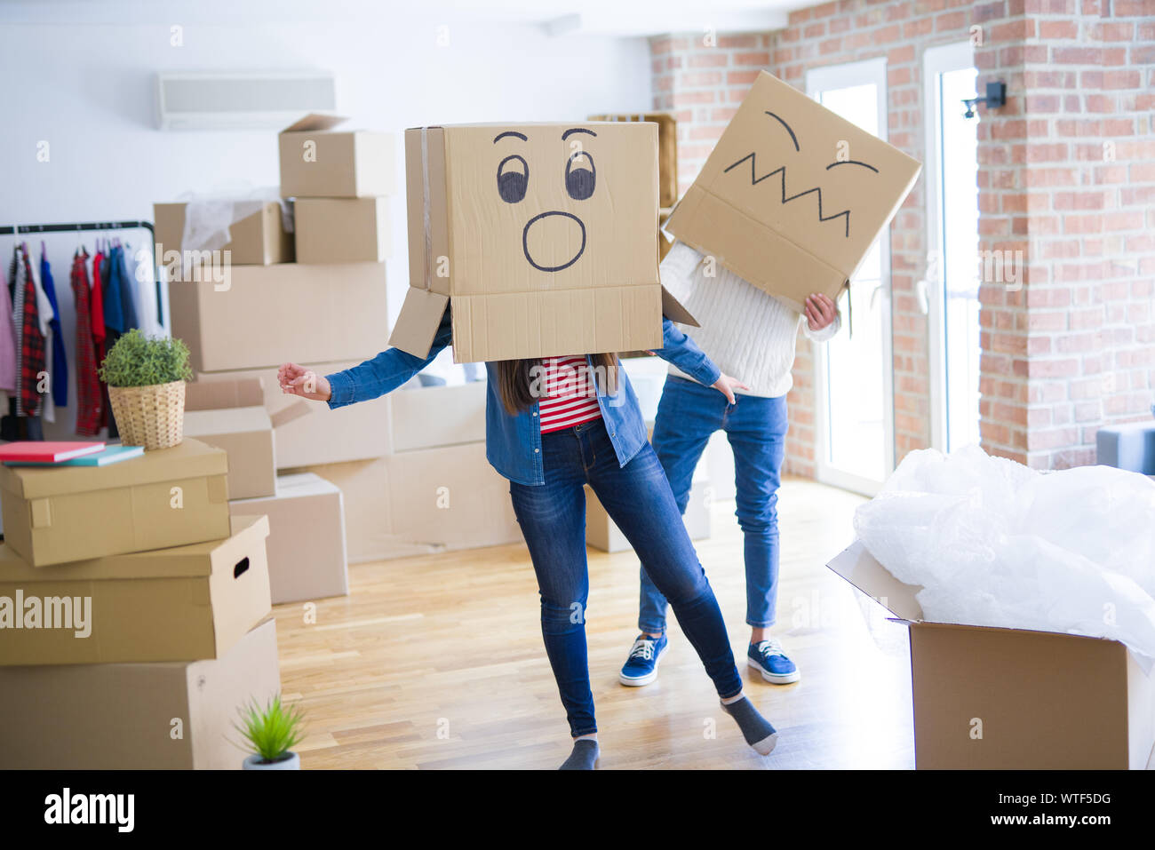 Crazy couple wearing boxes with funny faces over head, having fun happy ...