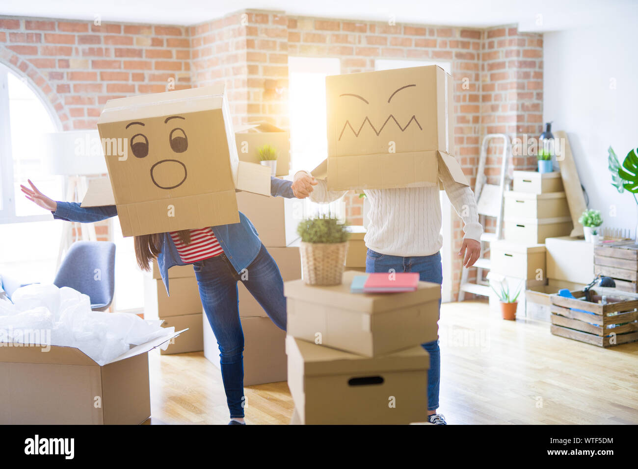 Crazy couple wearing boxes with funny faces over head, having fun happy ...