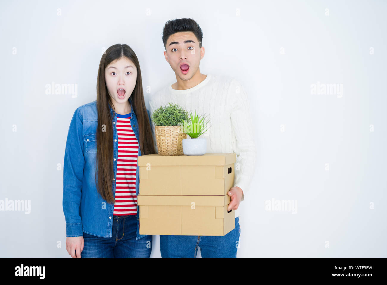 Beautiful young asian couple over white background holding cardboard ...