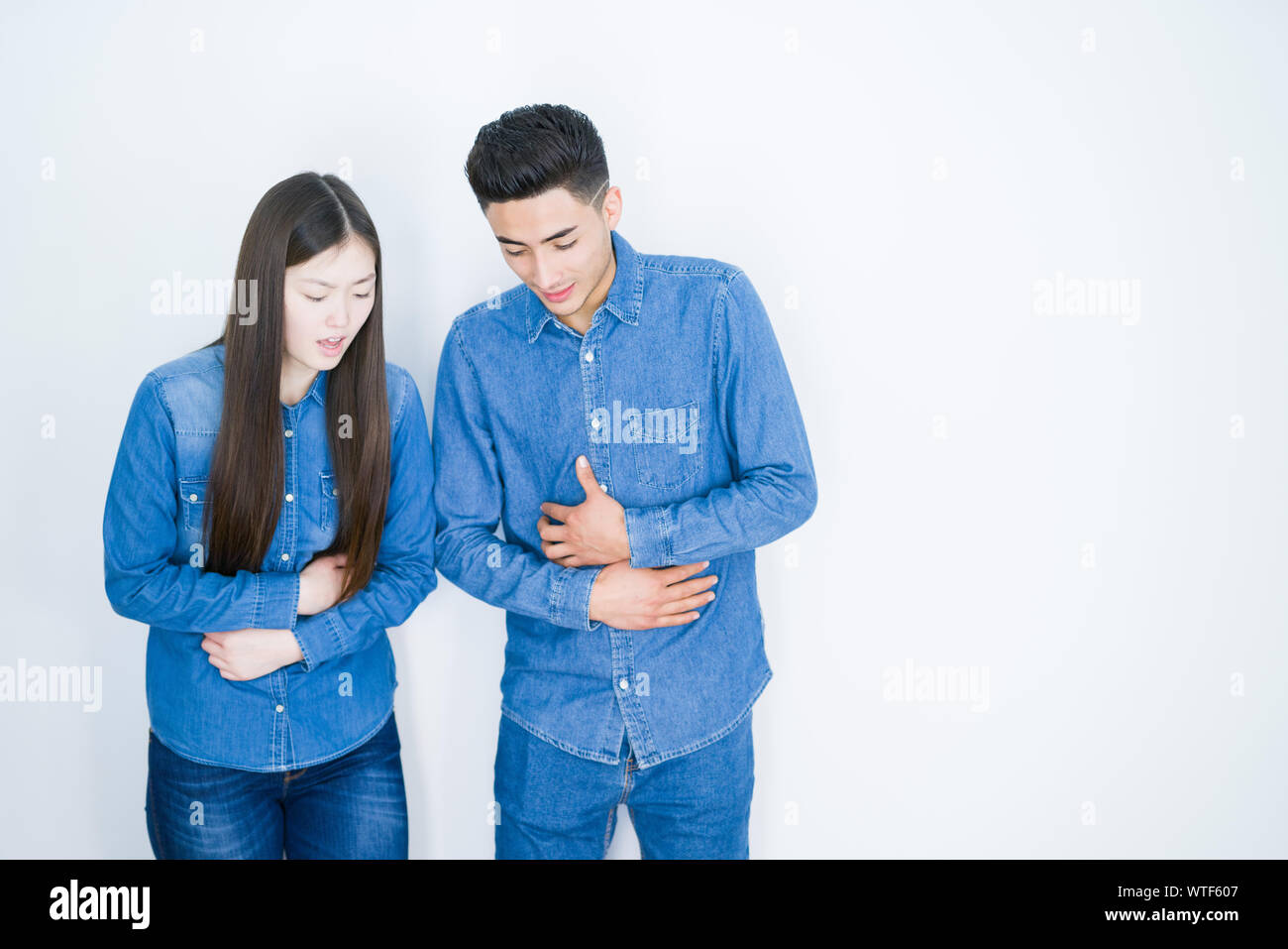 Beautiful young asian couple over white isolated background with hand ...
