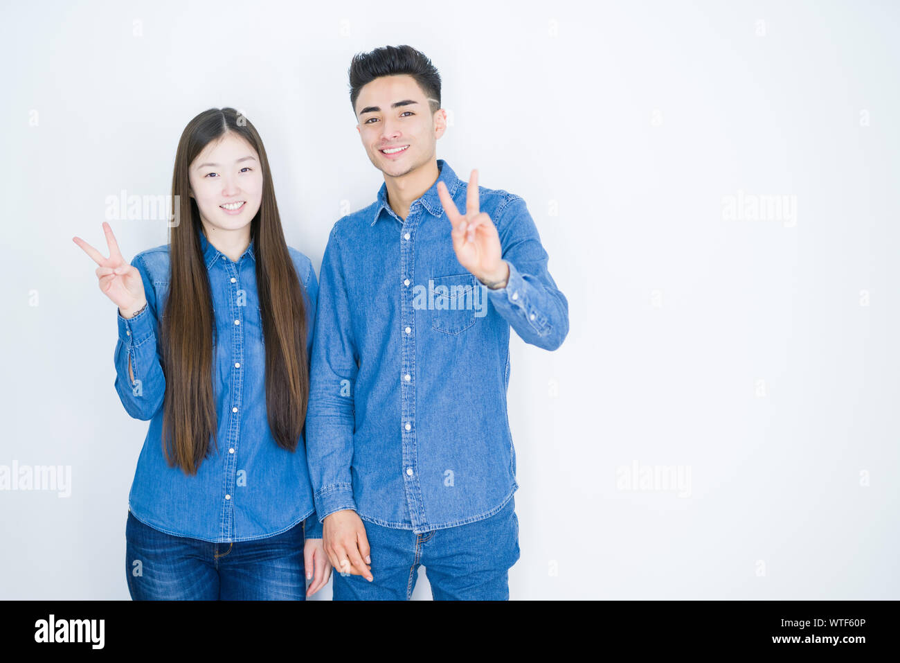 Beautiful young asian couple over white isolated background smiling ...