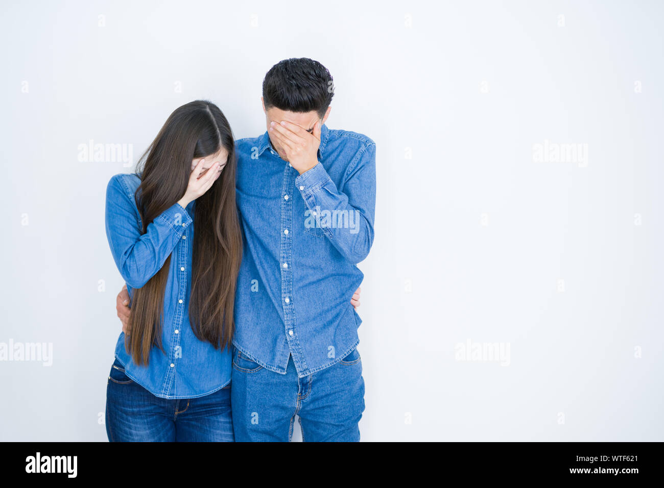 Beautiful young asian couple over white isolated background with sad ...