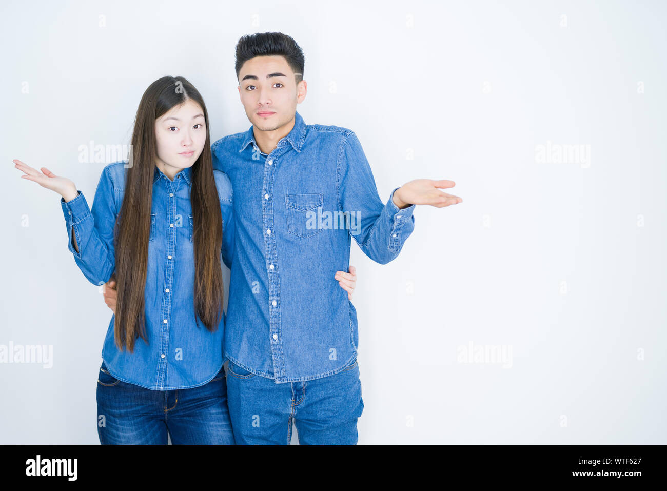 Beautiful young asian couple over white isolated background clueless ...