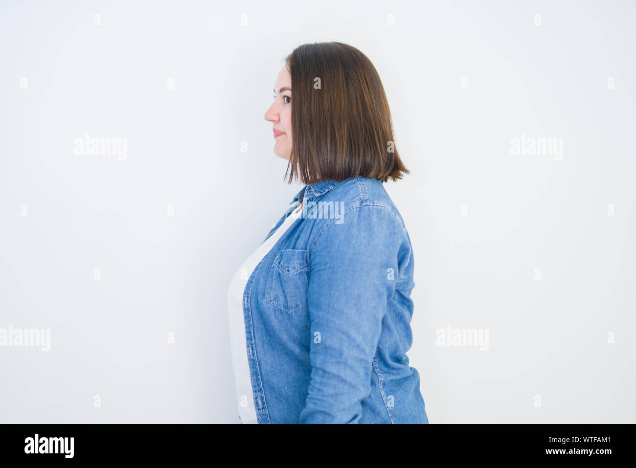 Young beautiful plus size woman over white isolated background looking ...
