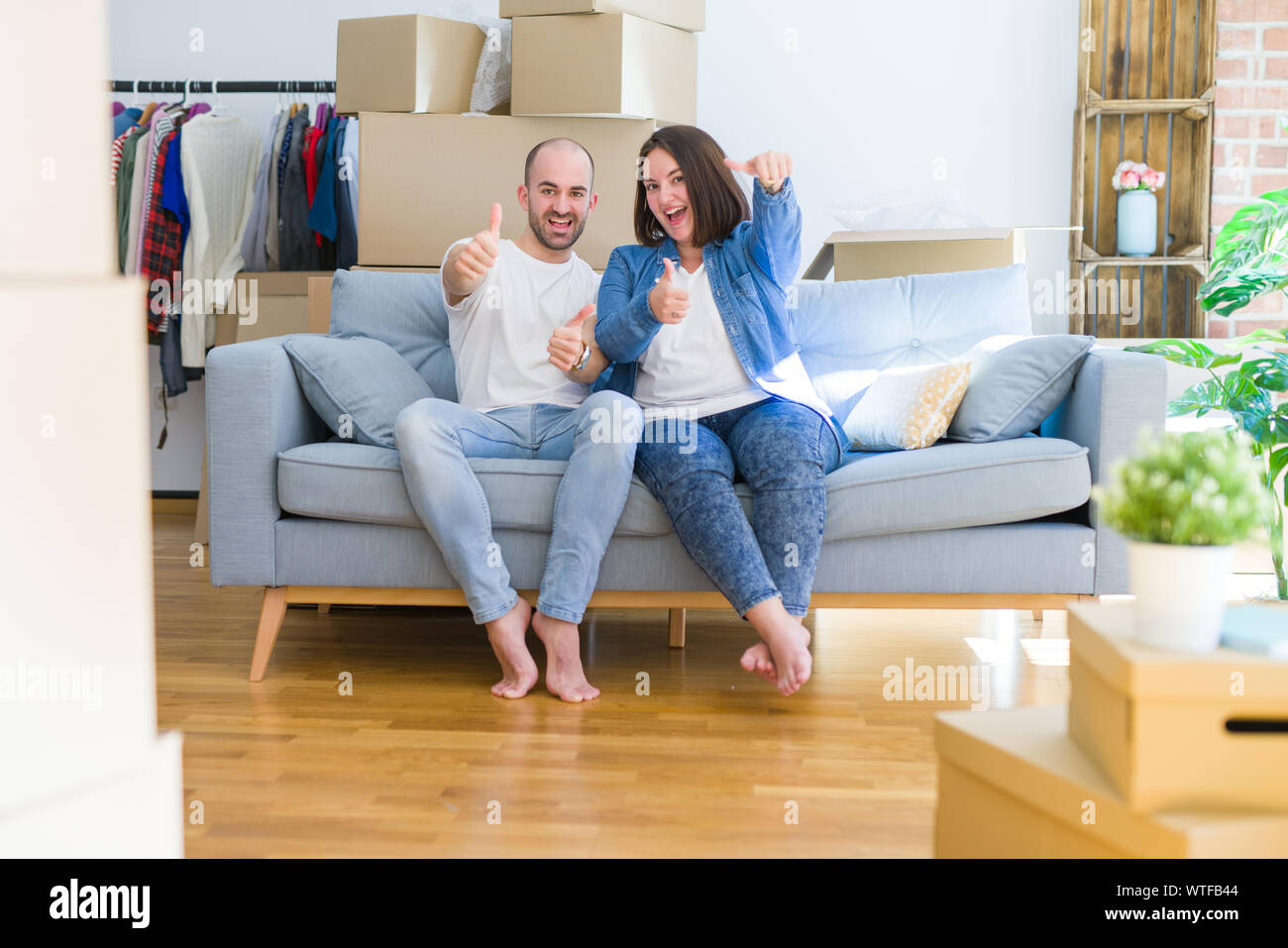 Young couple sitting on the sofa arround cardboard boxes moving to a ...