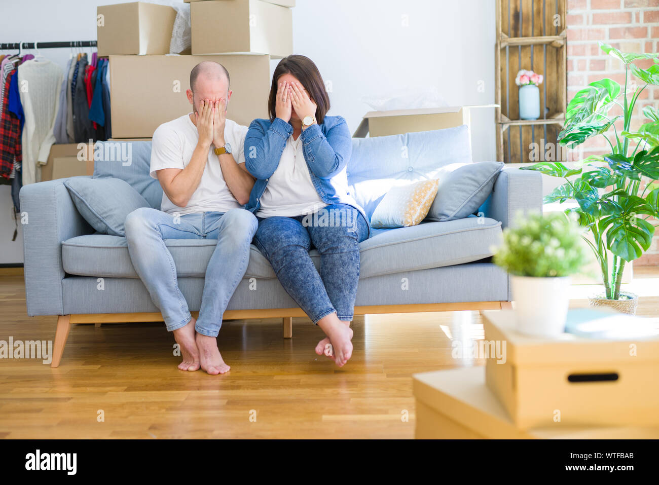 Young couple sitting on the sofa arround cardboard boxes moving to a ...