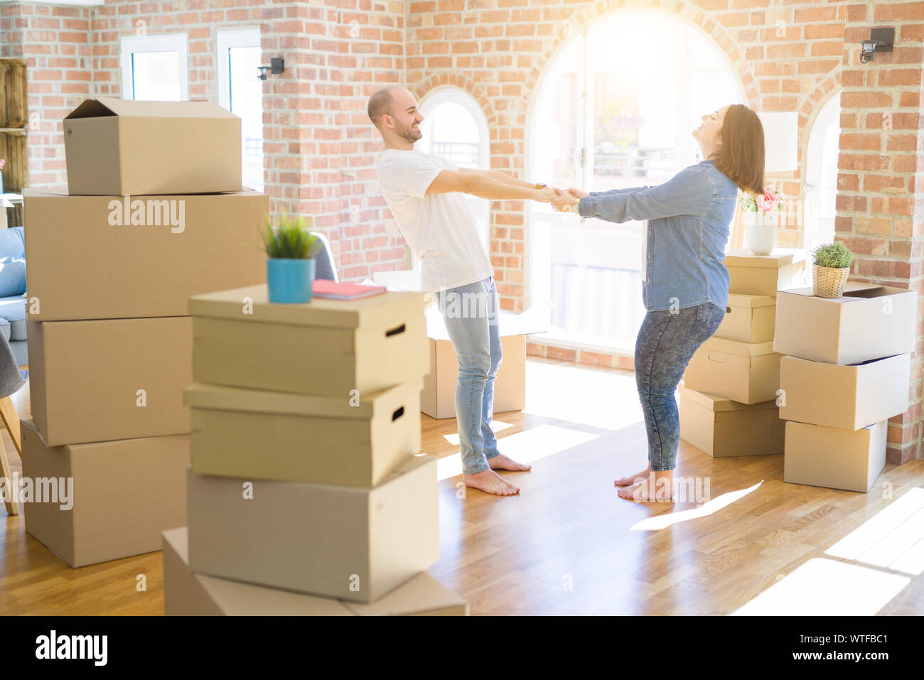 Young couple dancing around cardboard boxes at new home, celebrating ...