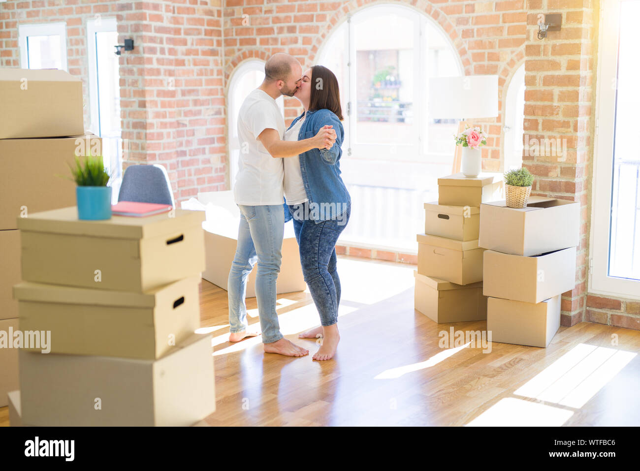 Young couple dancing around cardboard boxes at new home, celebrating ...