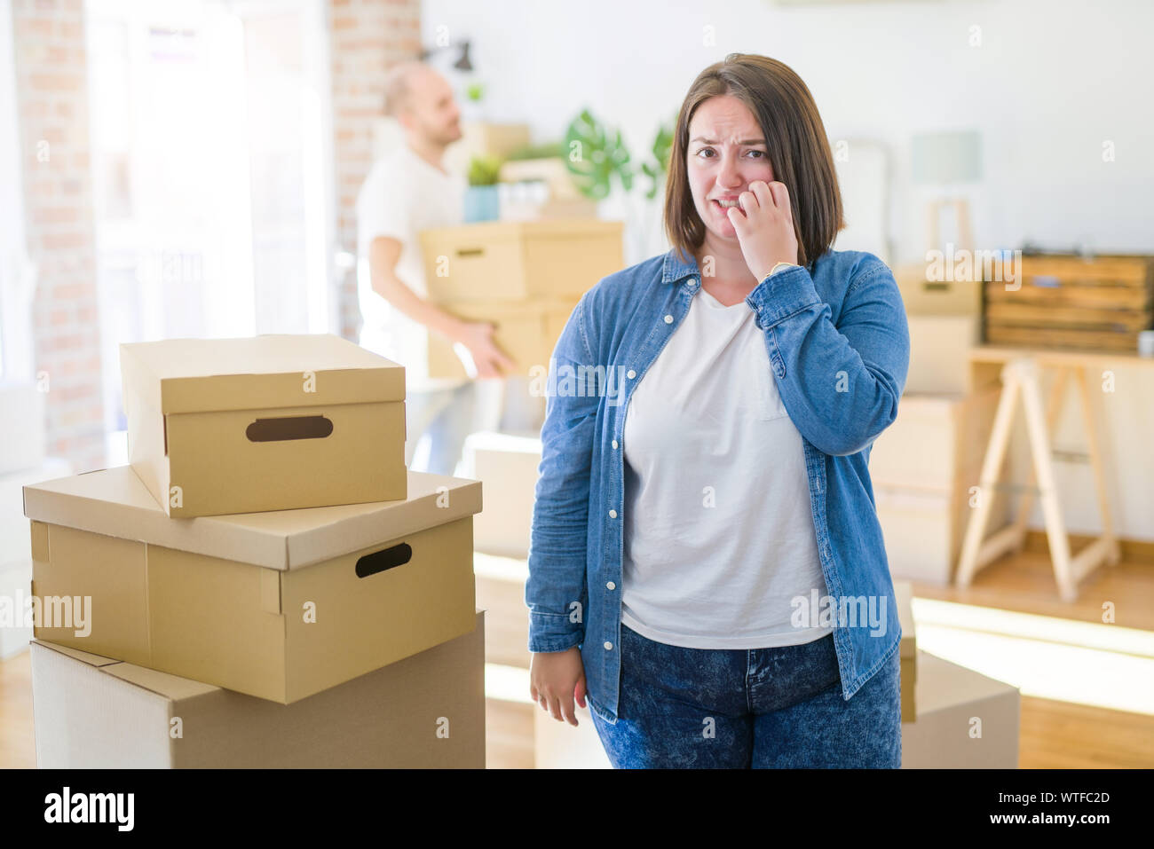 Young couple arround cardboard boxes moving to a new house, plus size ...